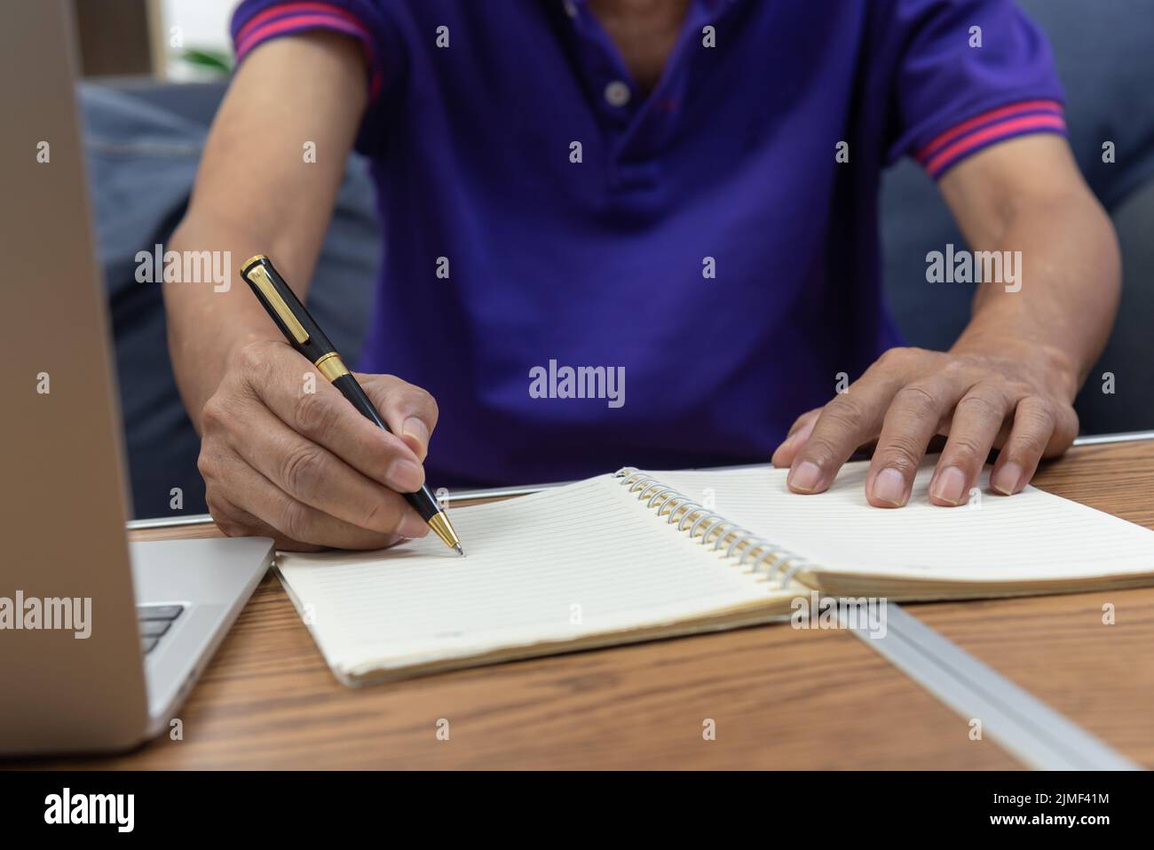 Asian elderly man holding pen write message note and computer laptop on ...