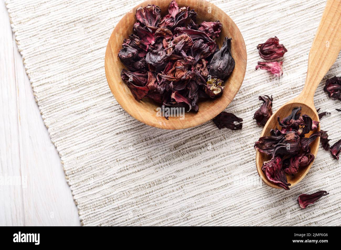 Top view at wooden bowl and spoon of dry hibiscus petals on linen cloth background Stock Photo ...