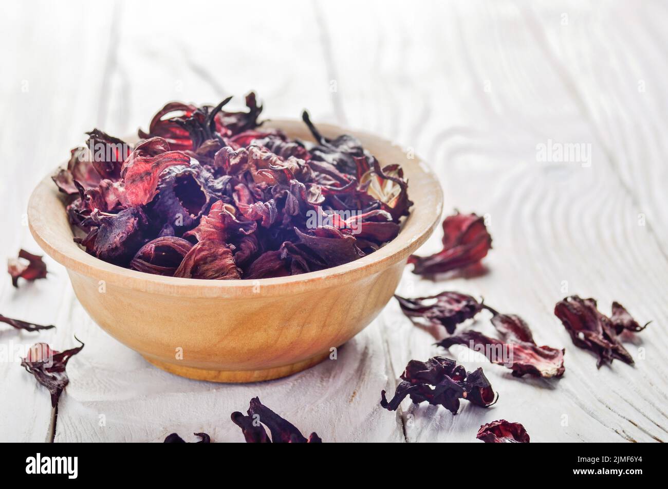 Closeup view at wooden bowl of dry hibiscus petals on white background Stock Photo - Alamy