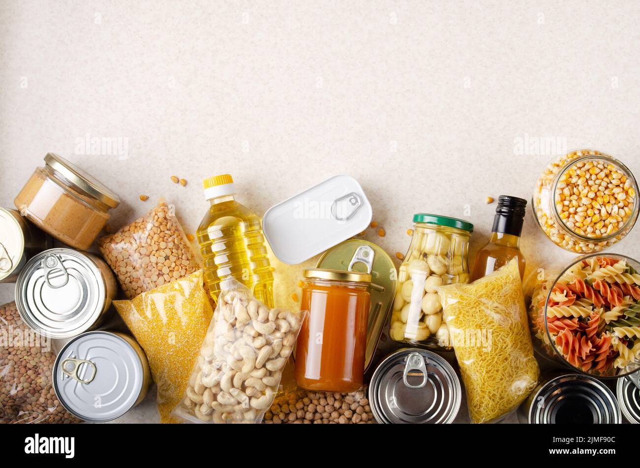 Flat lay view at kitchen table full with non-perishable foods. Spase ...