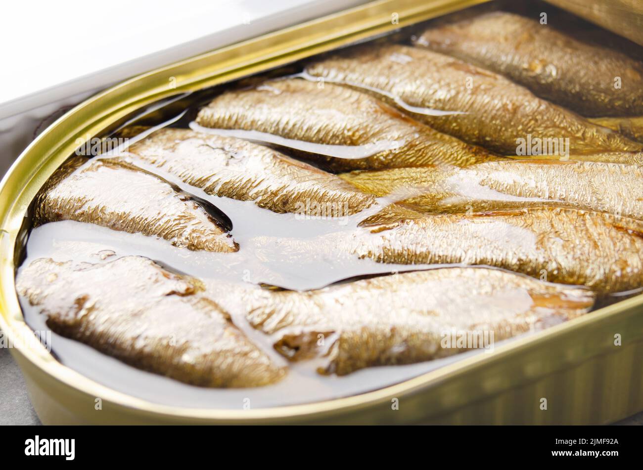 Canned smoked fish sprats in just opened tin can. Non-perishable food ...
