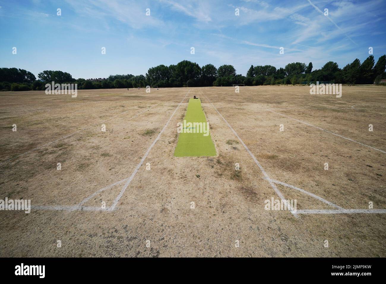 A green cricket pitch is surrounded by parched football pitches on ...