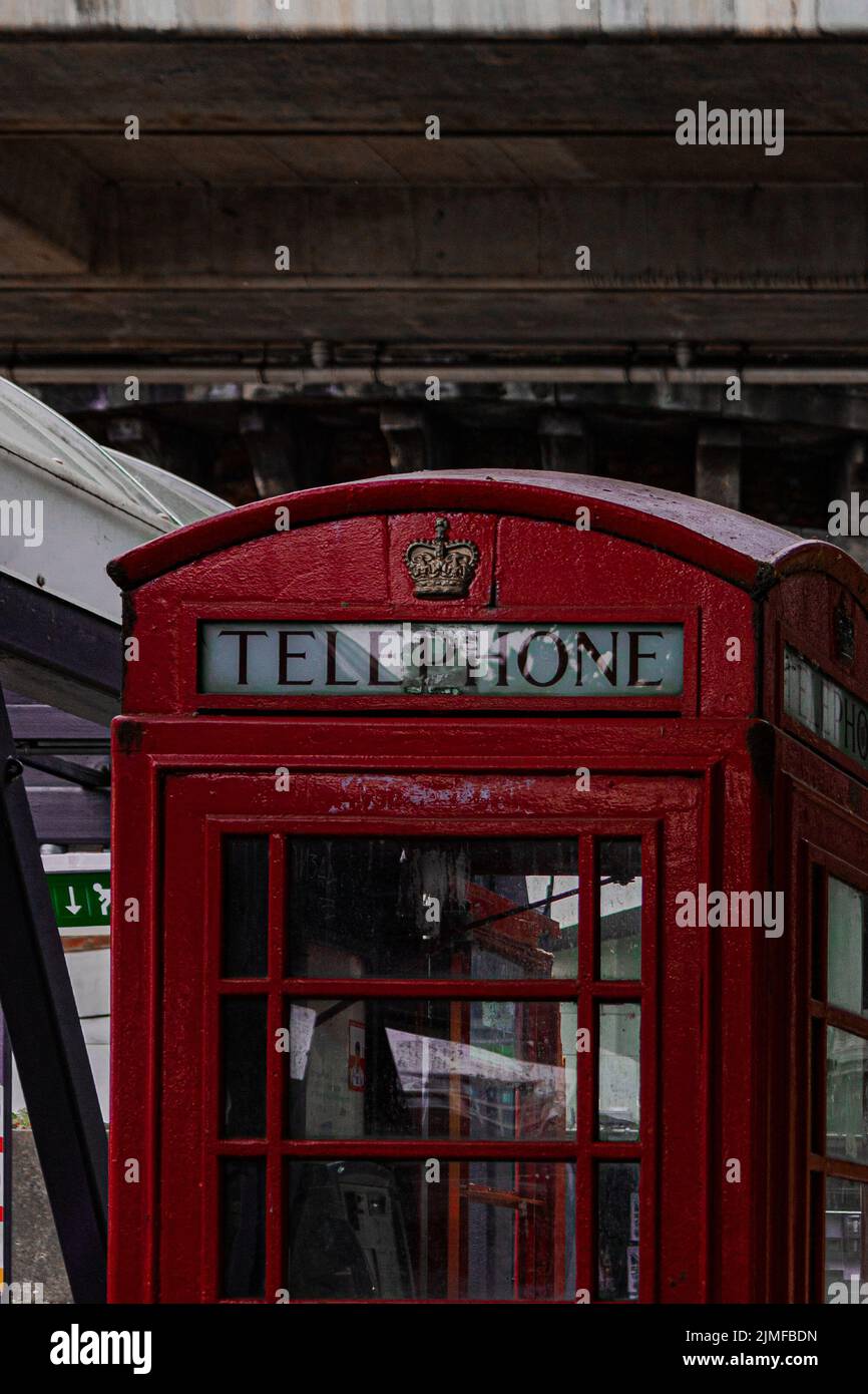 A vertical shot of a red telephone box with a sign saying Telephone in ...