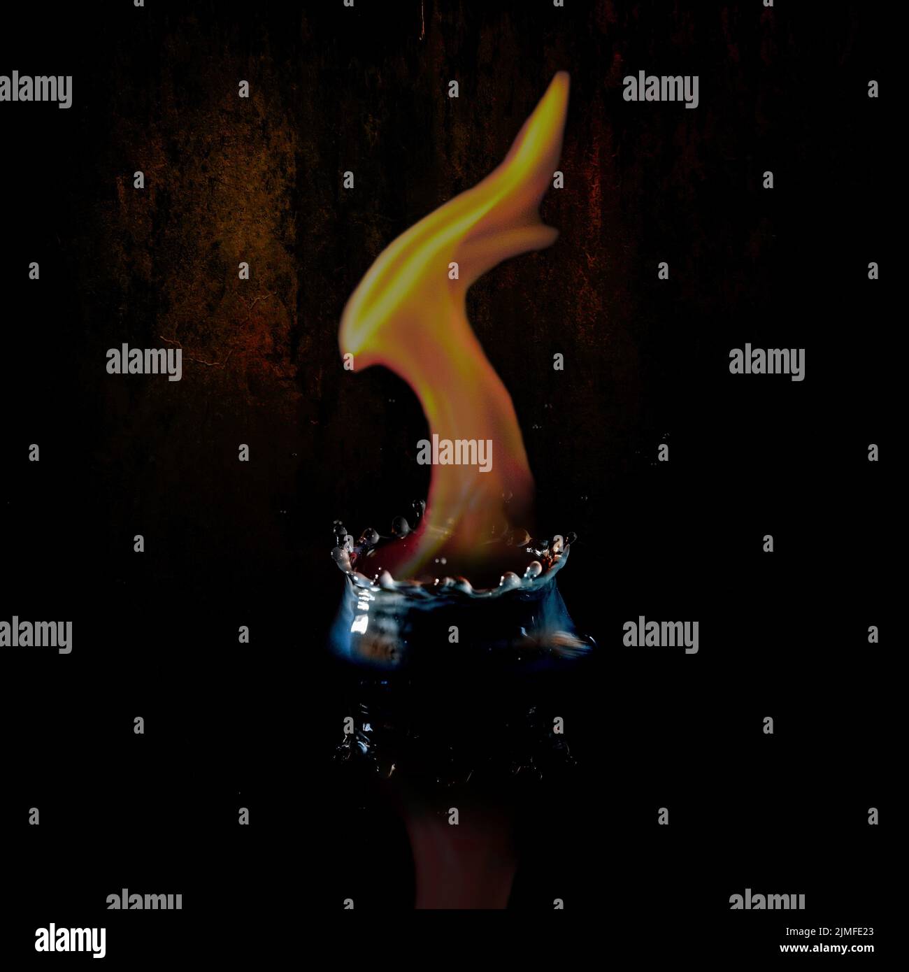 an orange flame emerging from a water splash on a black background, UK ...