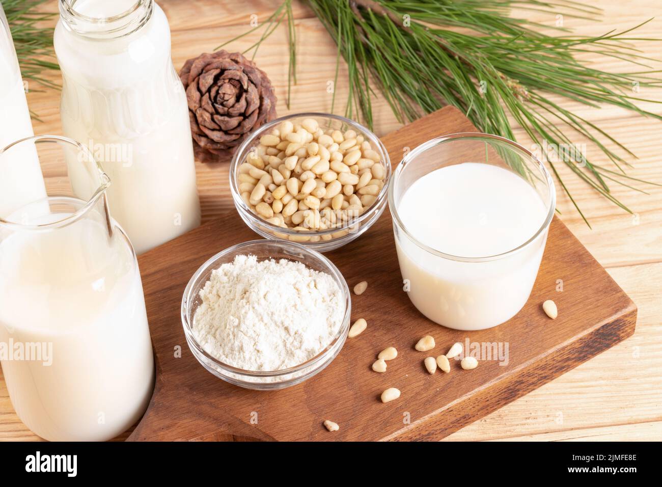 Cedar nut products: milk in glass and bottles, nuts and powder on ...