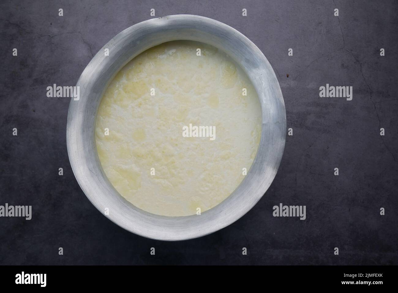 top view of full cream milk in a silver container on black background ...
