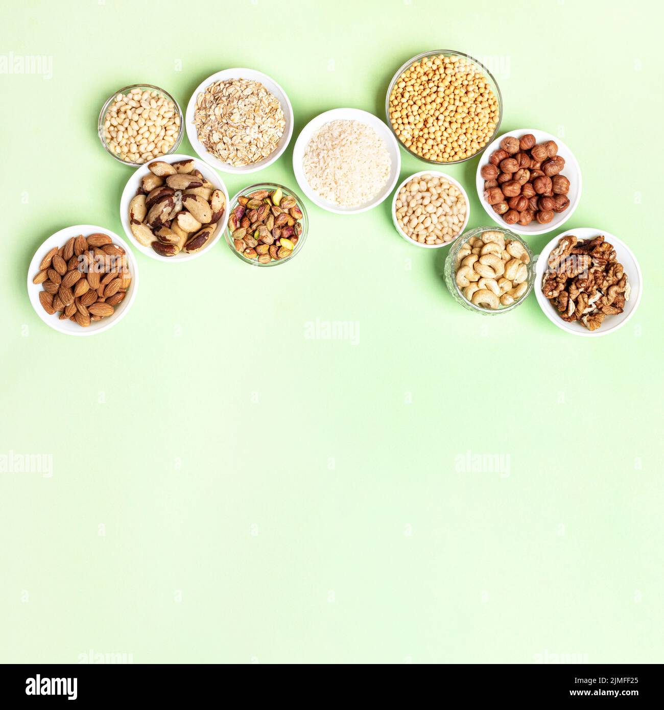 Different nuts and cereals in bowls on green background. Vegan protein ...