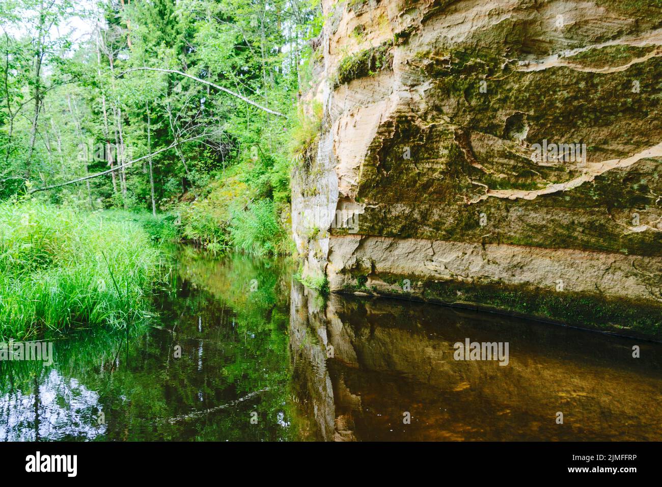 summer landscape with sandstone rock outcrop on the bank of a small ...