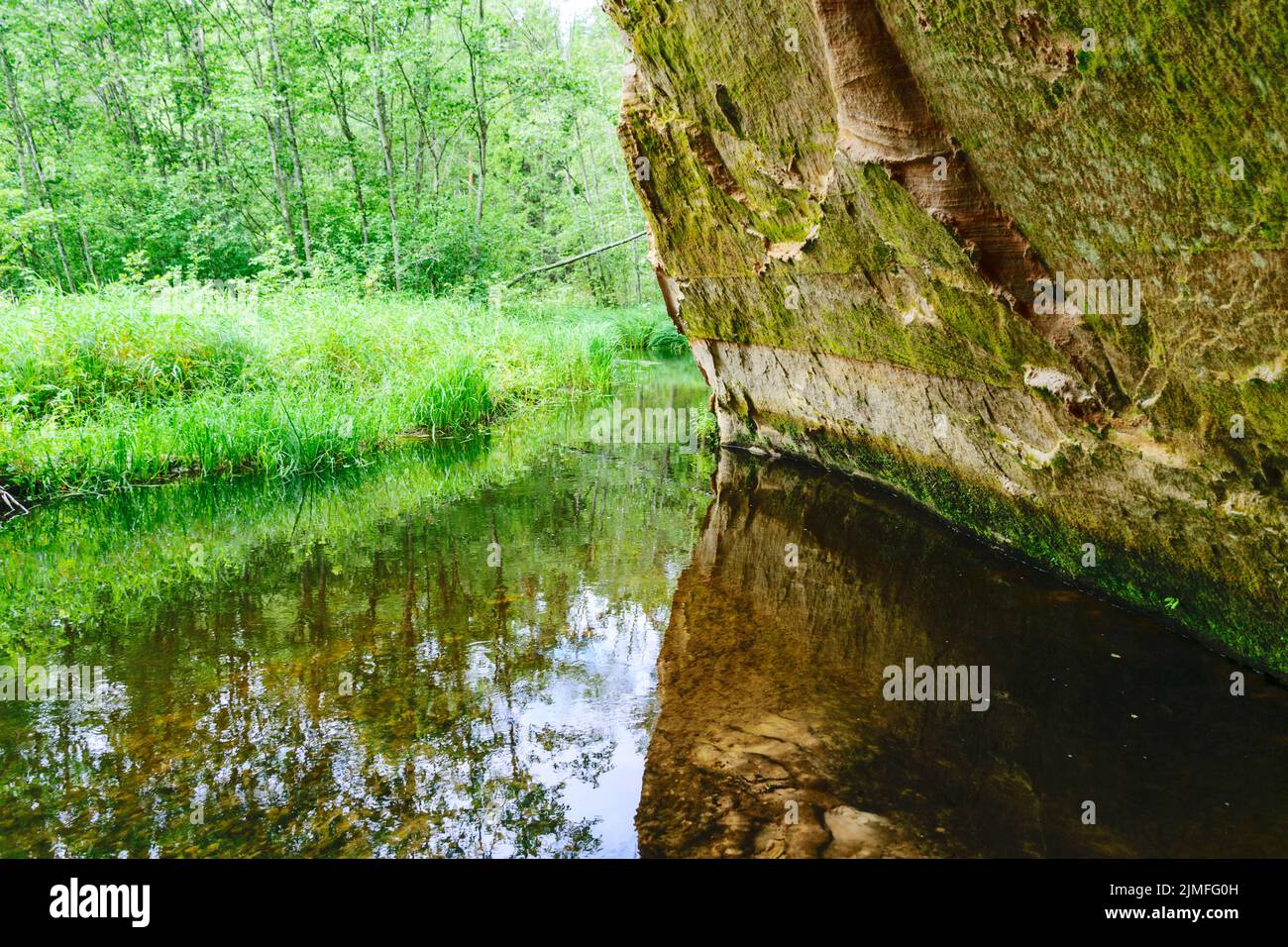 summer landscape with sandstone rock outcrop on the bank of a small ...