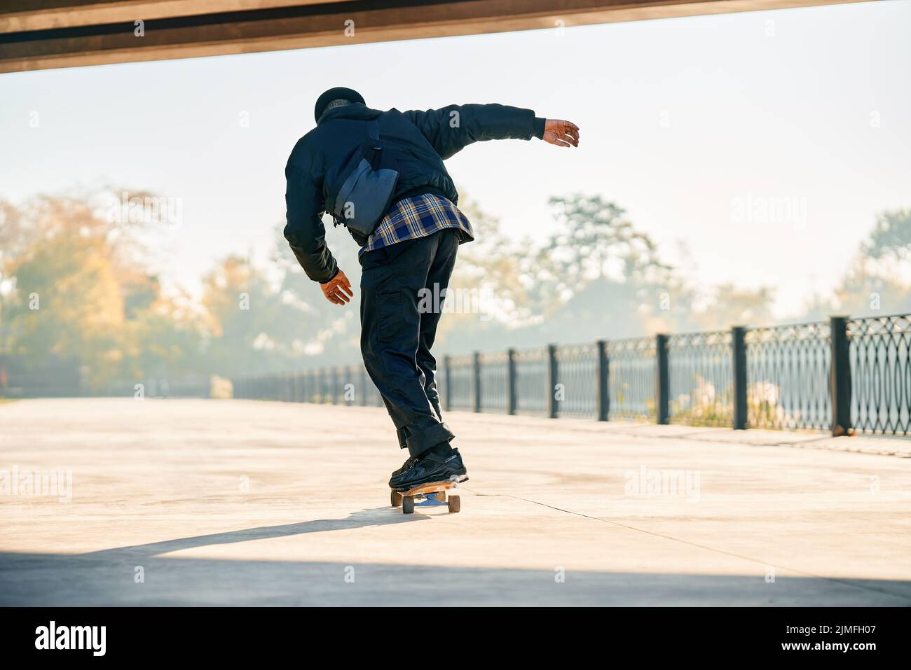 Back view of skateboarder skateboarding on the street urban background ...