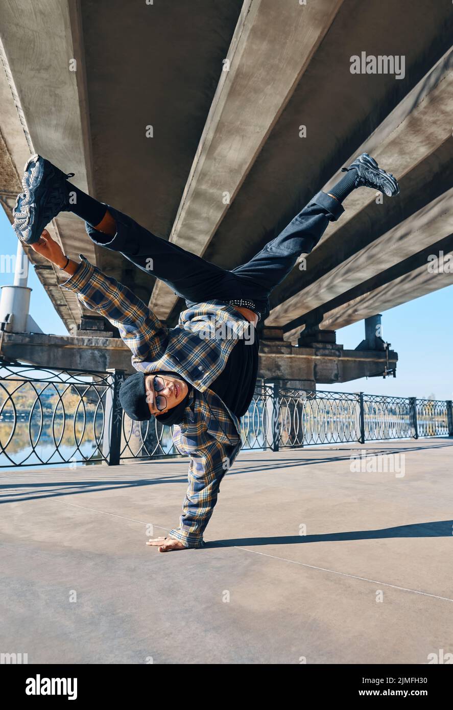 Young man break dancer dancing on urban background performing acrobatic ...