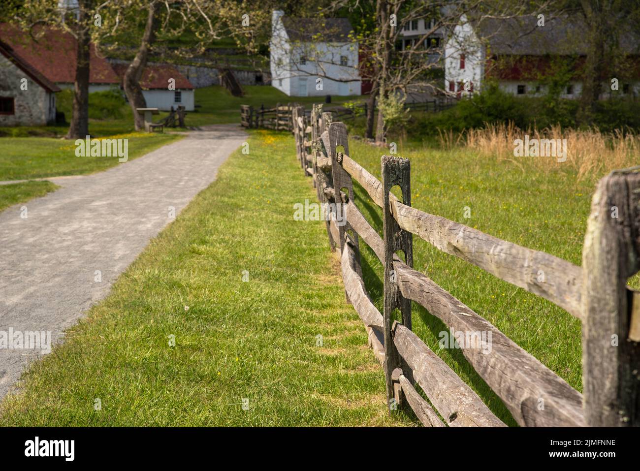 Wooden fence along walking path leads to colonial American village ...
