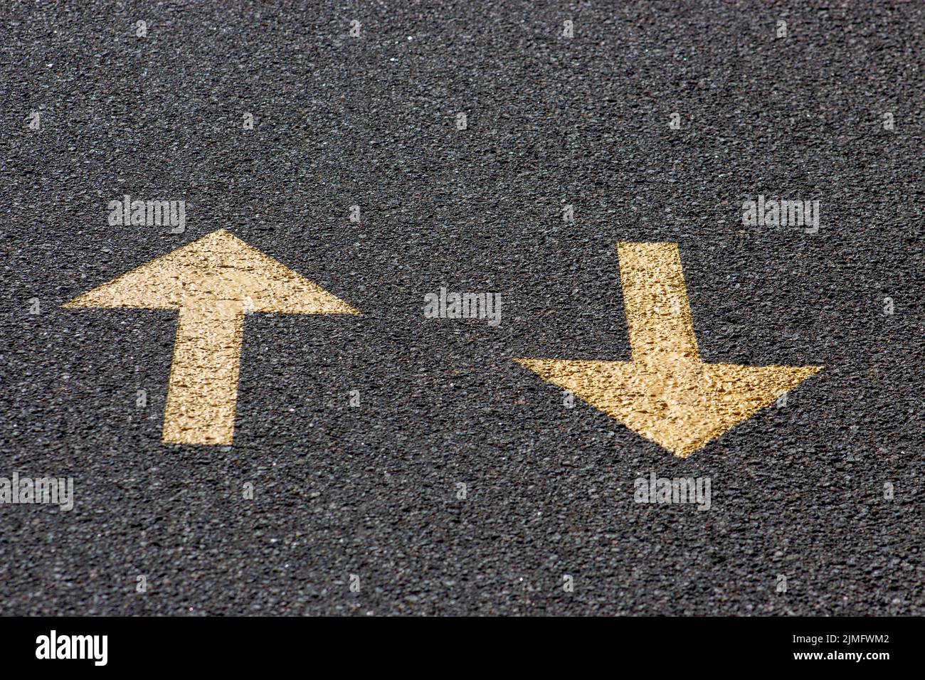 Yellow arrows on the asphalt road, back and forth Stock Photo - Alamy