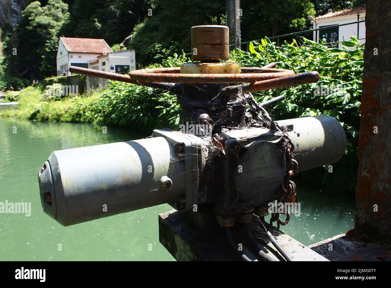 Rusty electric valve, covered in spiderweb, with padlocked chain, on a ...