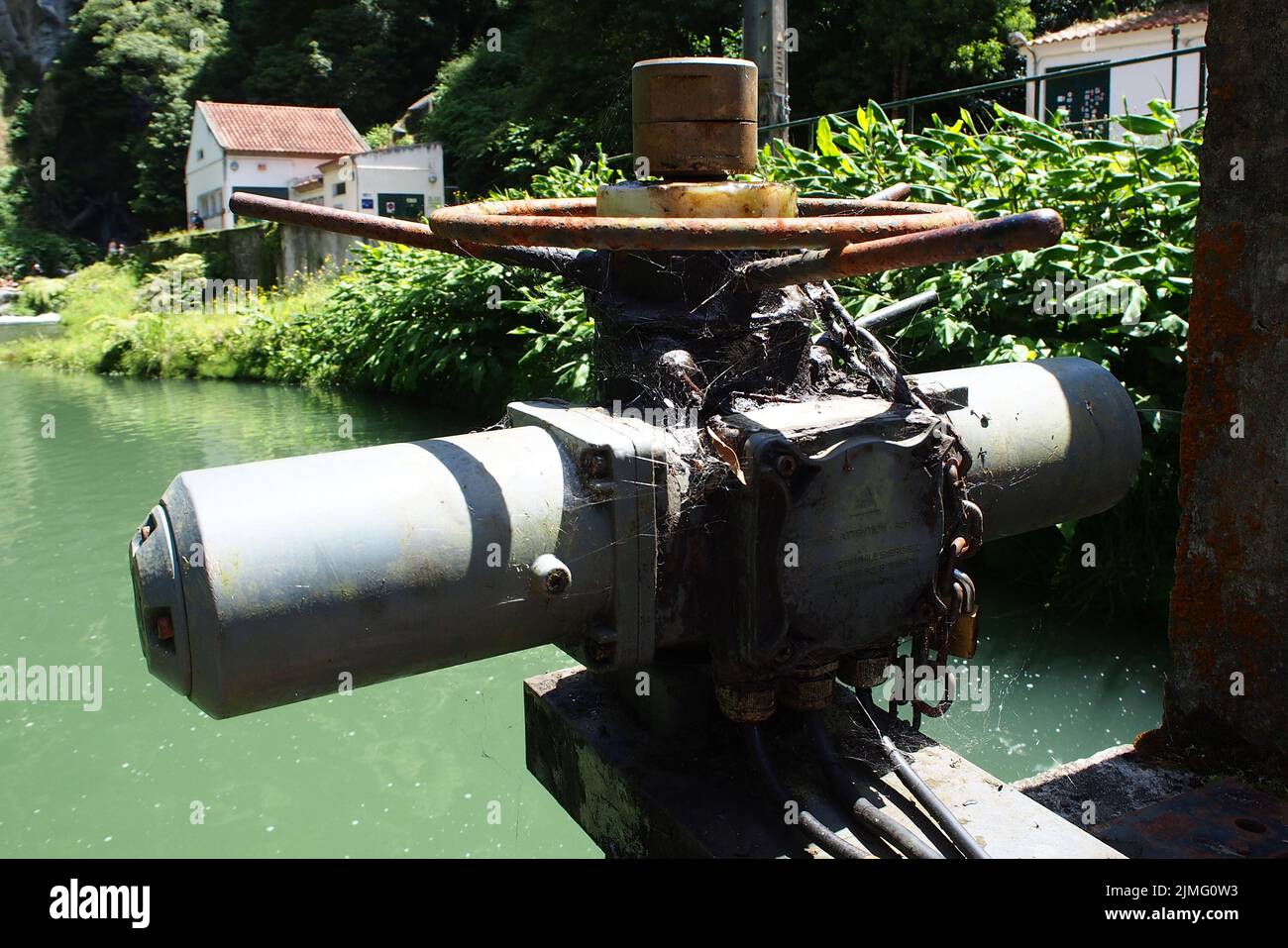 Rusty electric valve, covered in spiderweb, with padlocked chain, on a ...