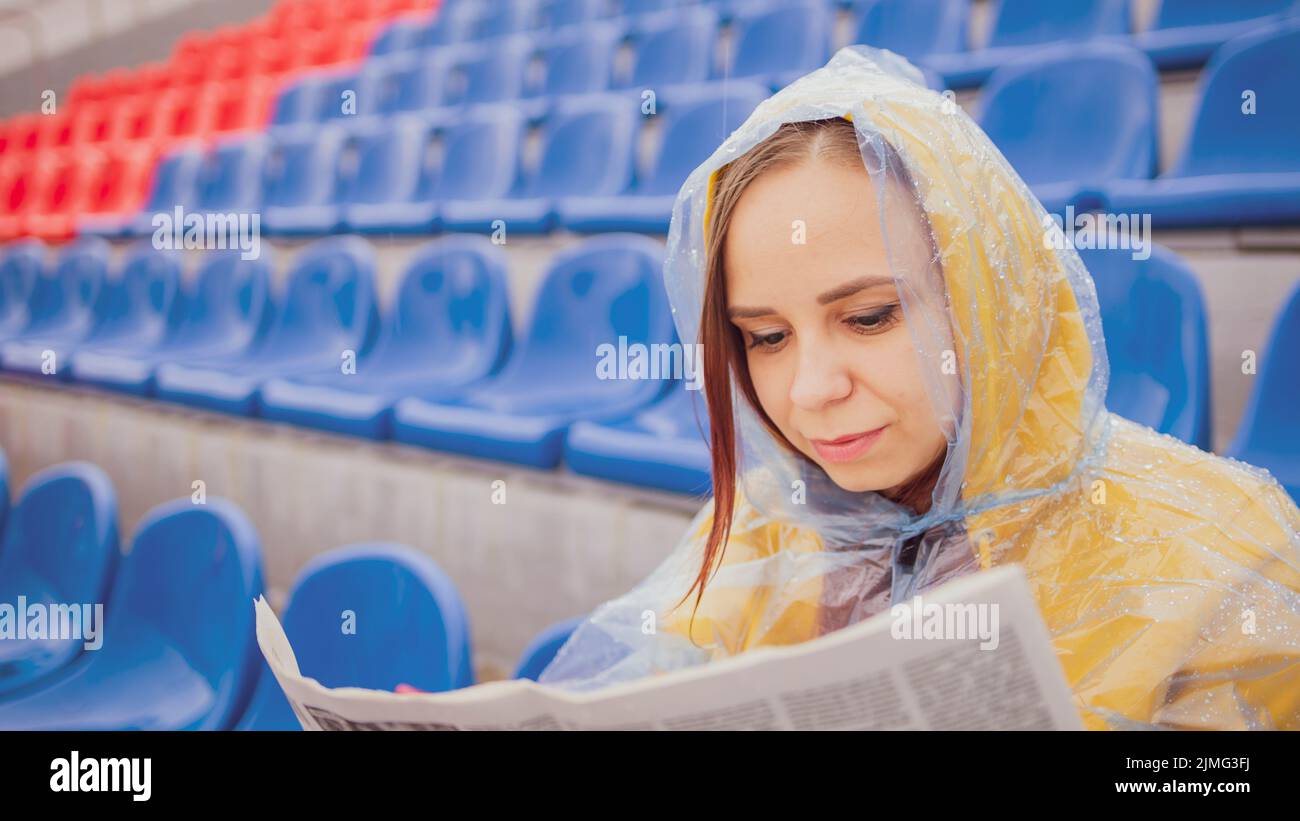 A beautiful woman in a hoodie and a plastic raincoat, learns the latest ...