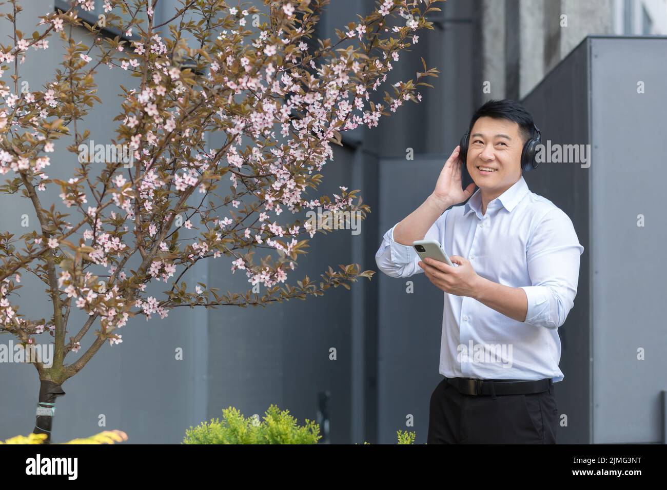 Cheerful and smiling successful Asian business man listening to music ...
