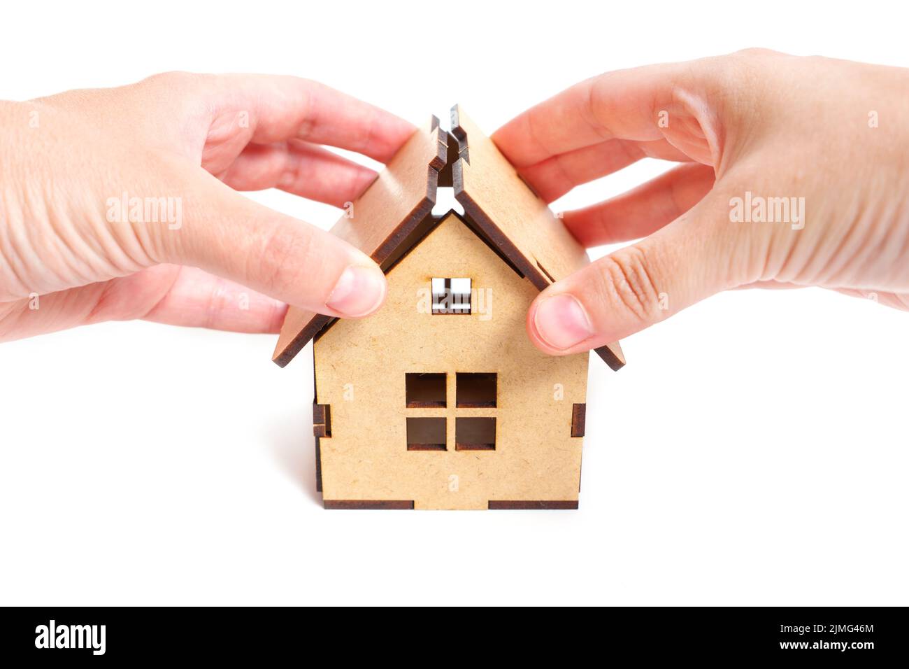Hands assembling roof elements of a wooden toy house model isolated on ...