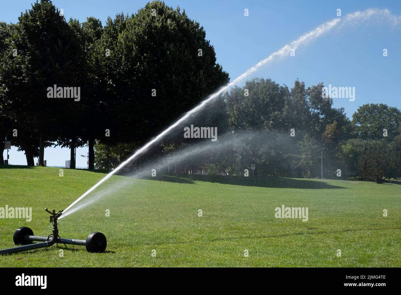 Mobile irrigation system water on a green lawn during a dry summer ...