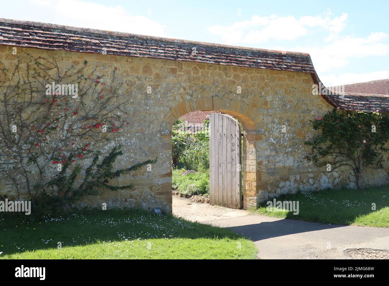 An arched gateway with an old wooden door leads in to the kitchen ...