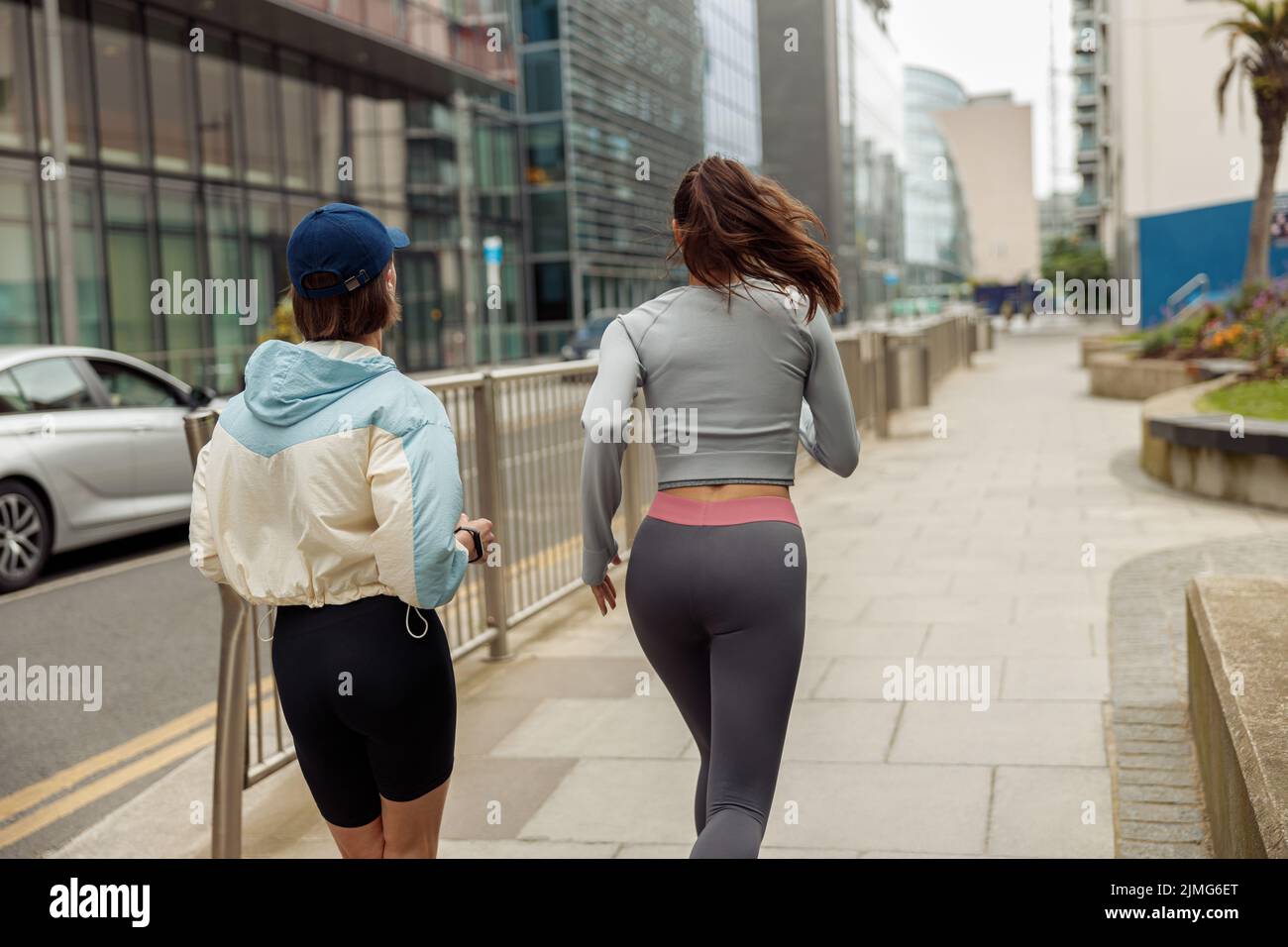 Back view of two athletic women in sportswear are running around the ...