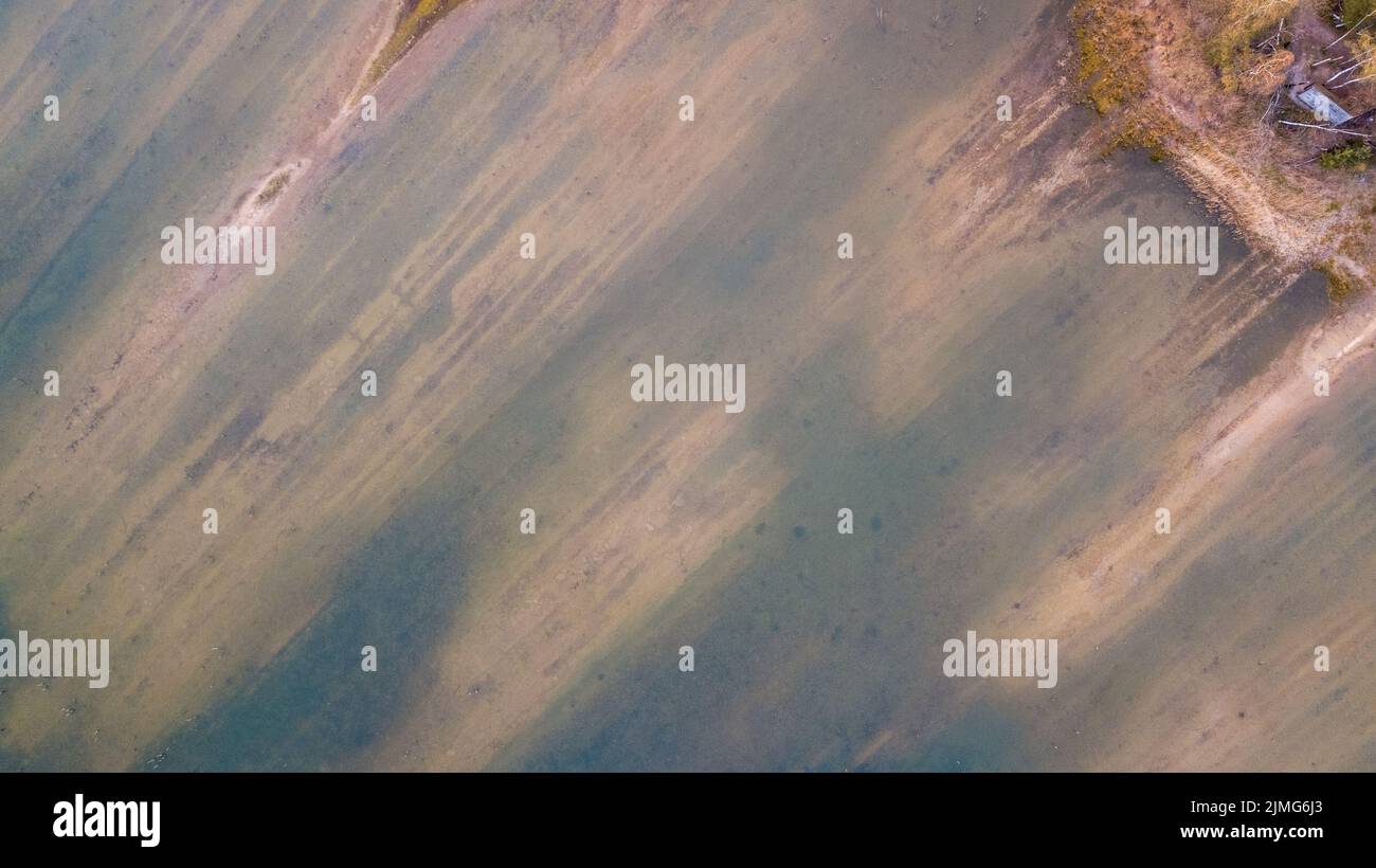 Aerial view shot by a drone of the shore of a forest lake. Thick grass ...