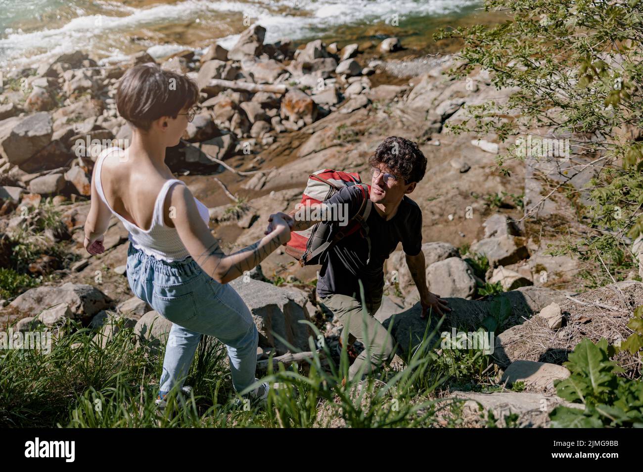 Couple climbing up by cliffs and rocks at mountains and river. Hand of ...