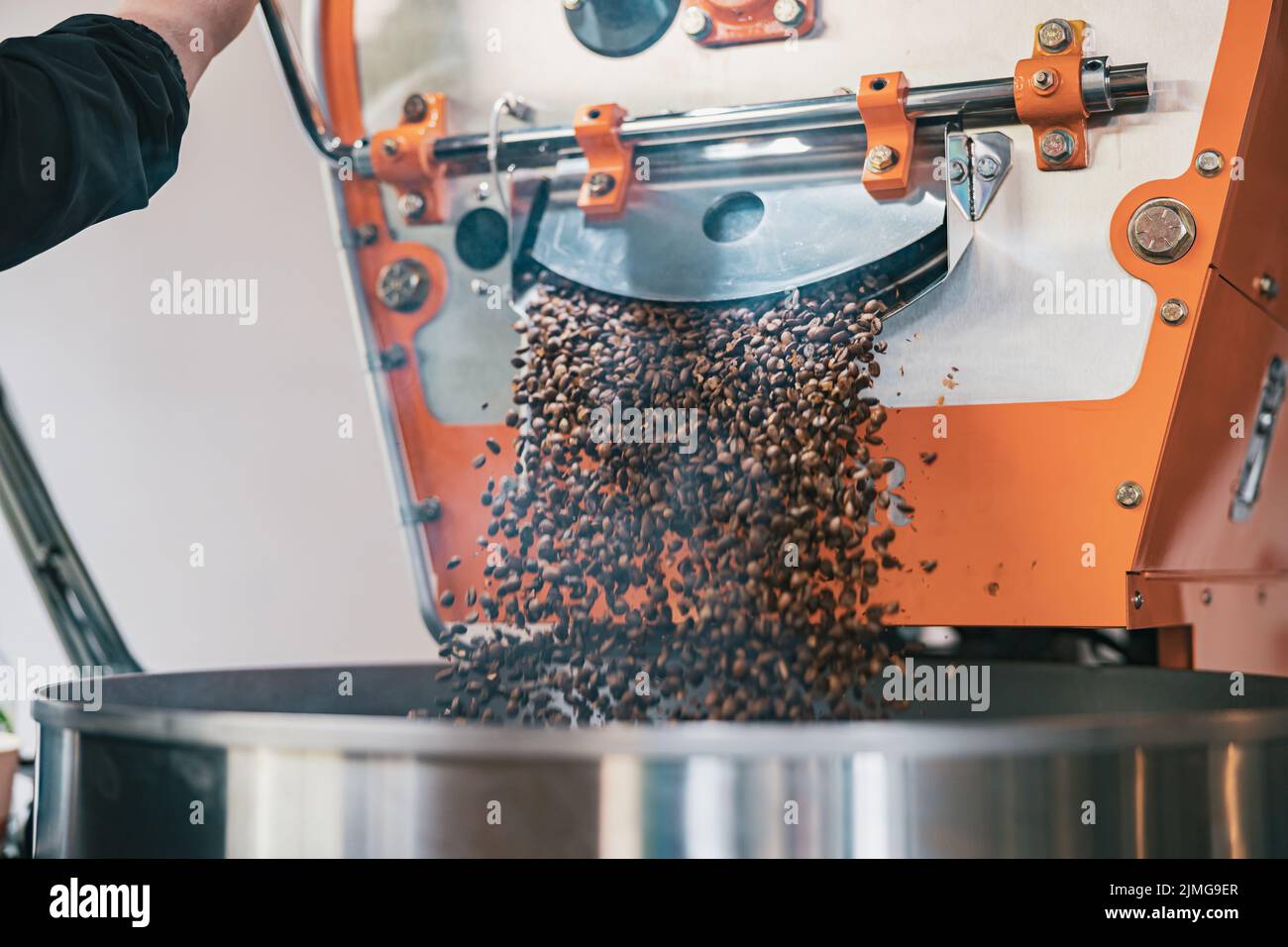 Close up of Business owner pouring roasted coffee beans from large ...