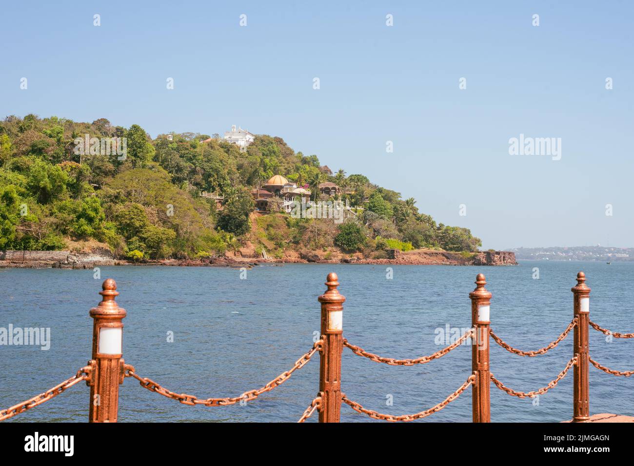 The orange pillar chain fence along the shore with lush green hill in ...