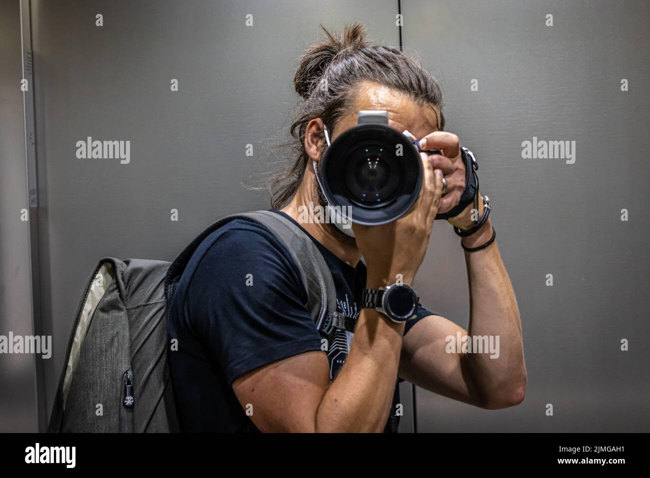 A German man with long hair shooting himself in a mirror with camera ...