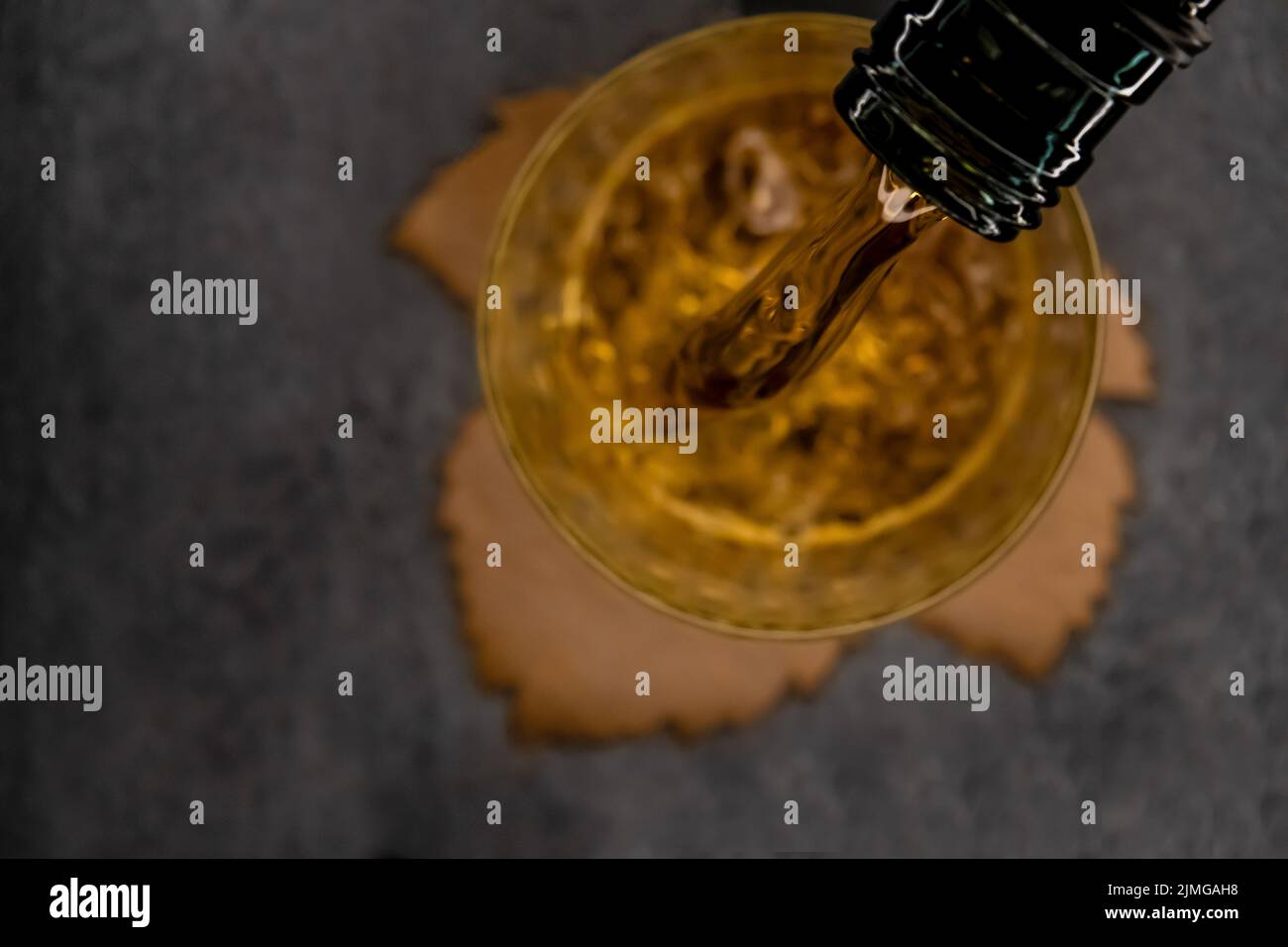 A top view of alcohol being poured into a glass on leaf-shaped stand ...