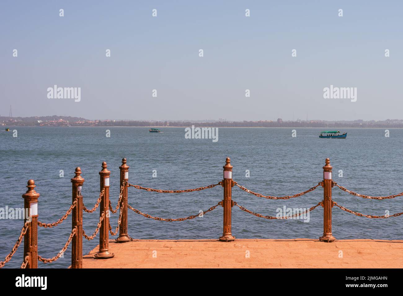 The orange pillar chain fence along the shore with boats in the ...