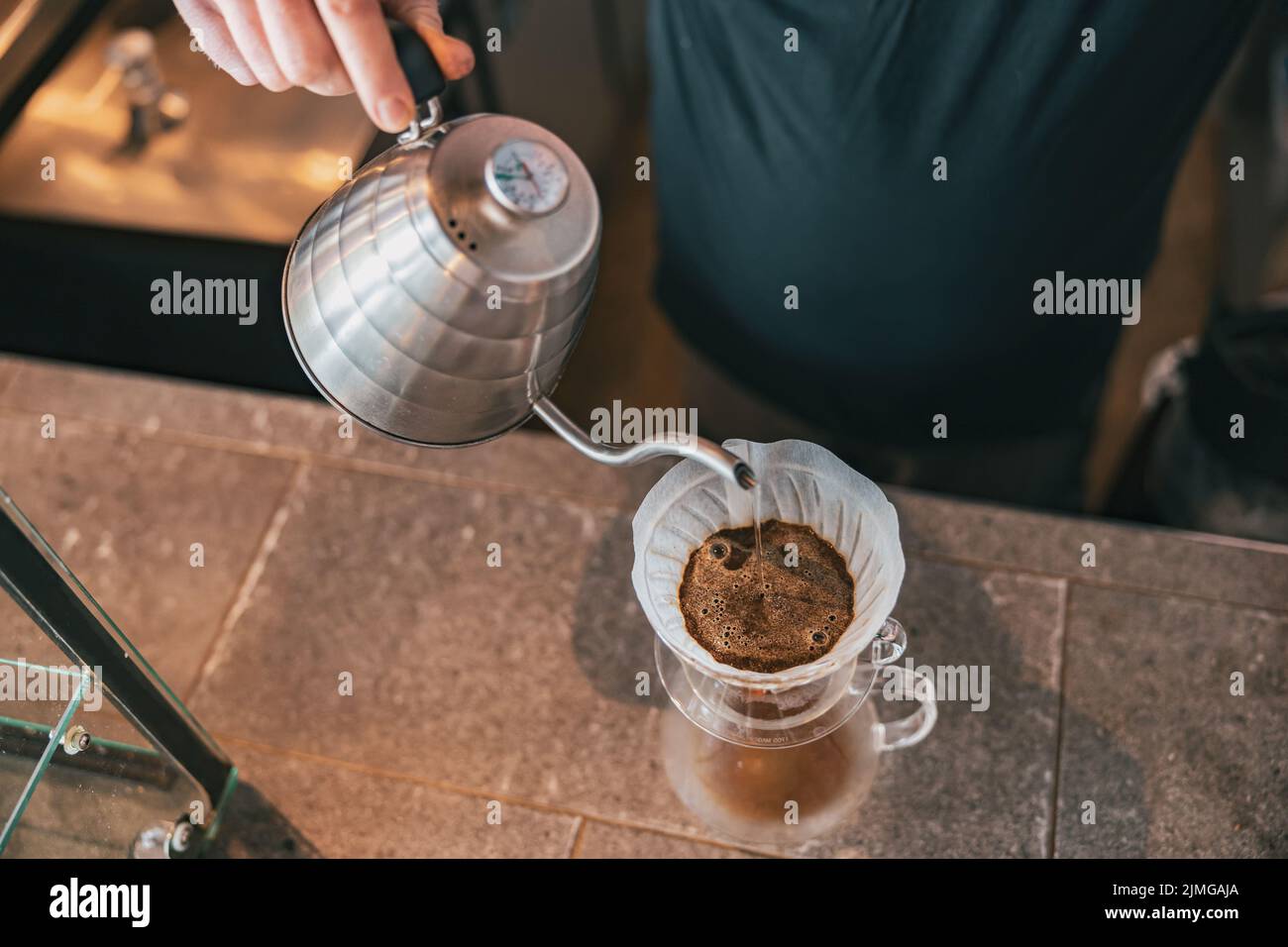 Close up of barista pouring water on coffee ground with filter. Hand ...
