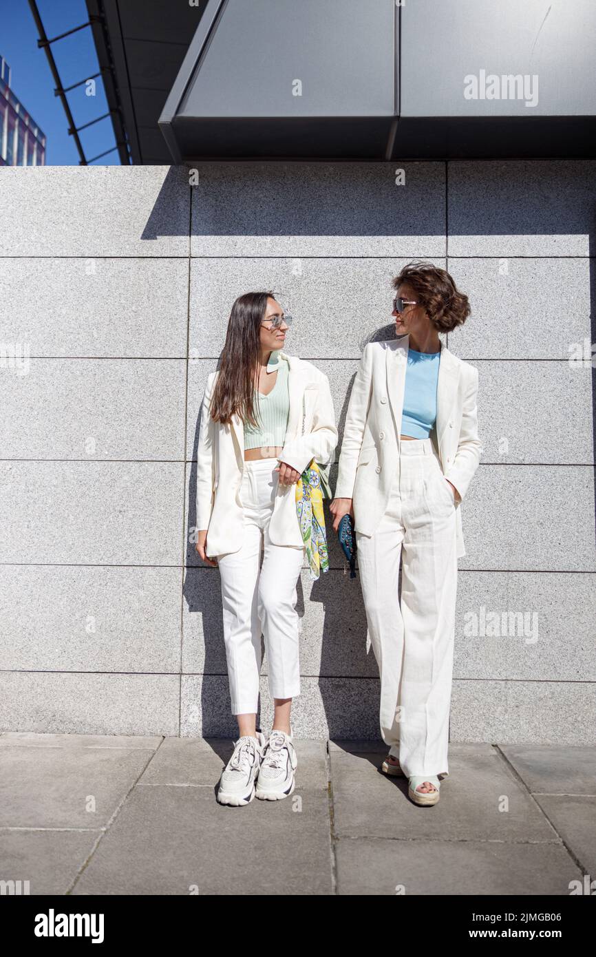 Two women standing near a wall smiling hi-res stock photography and ...