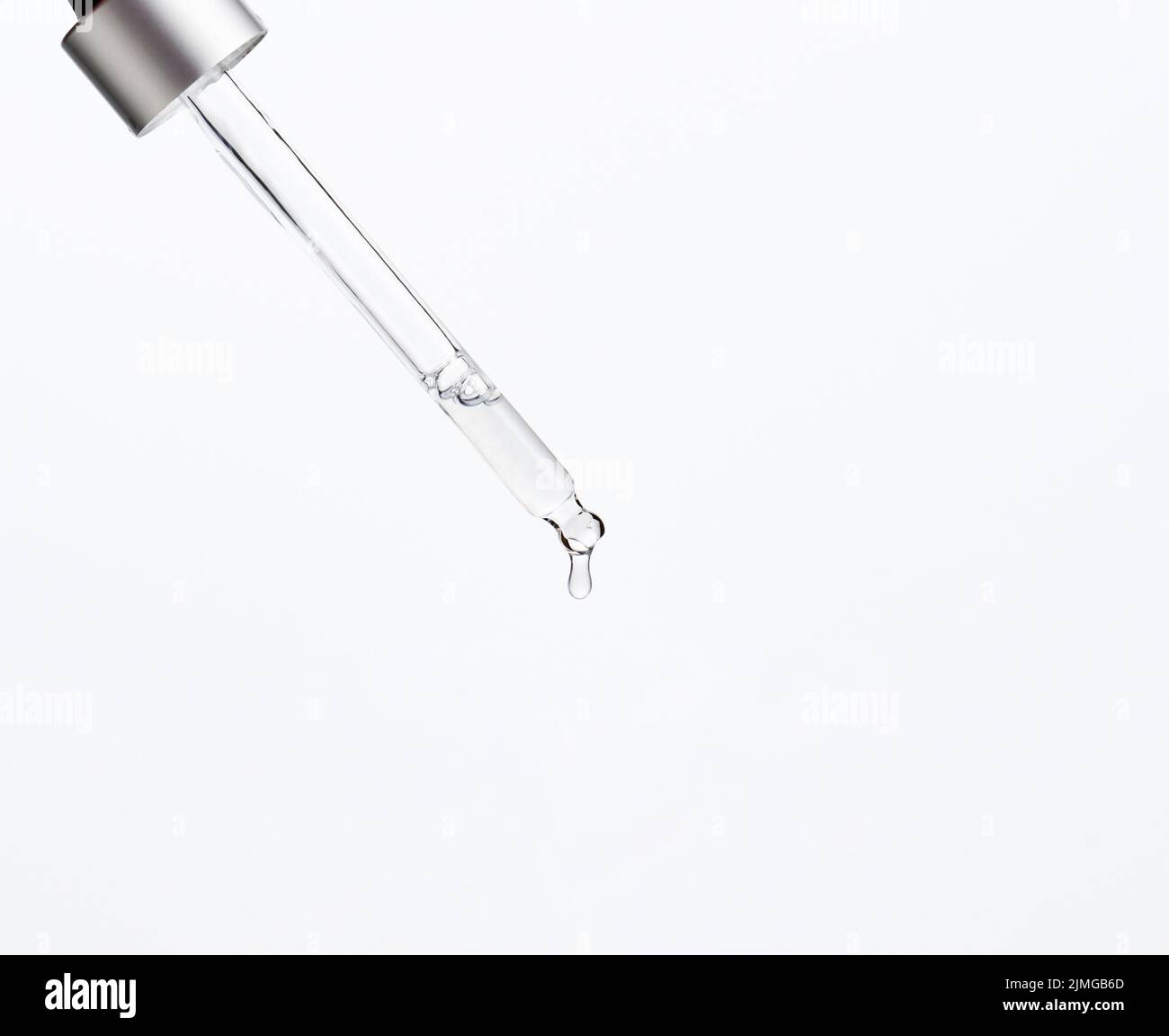 Glass pipette with dripping transparent liquid on a white background ...