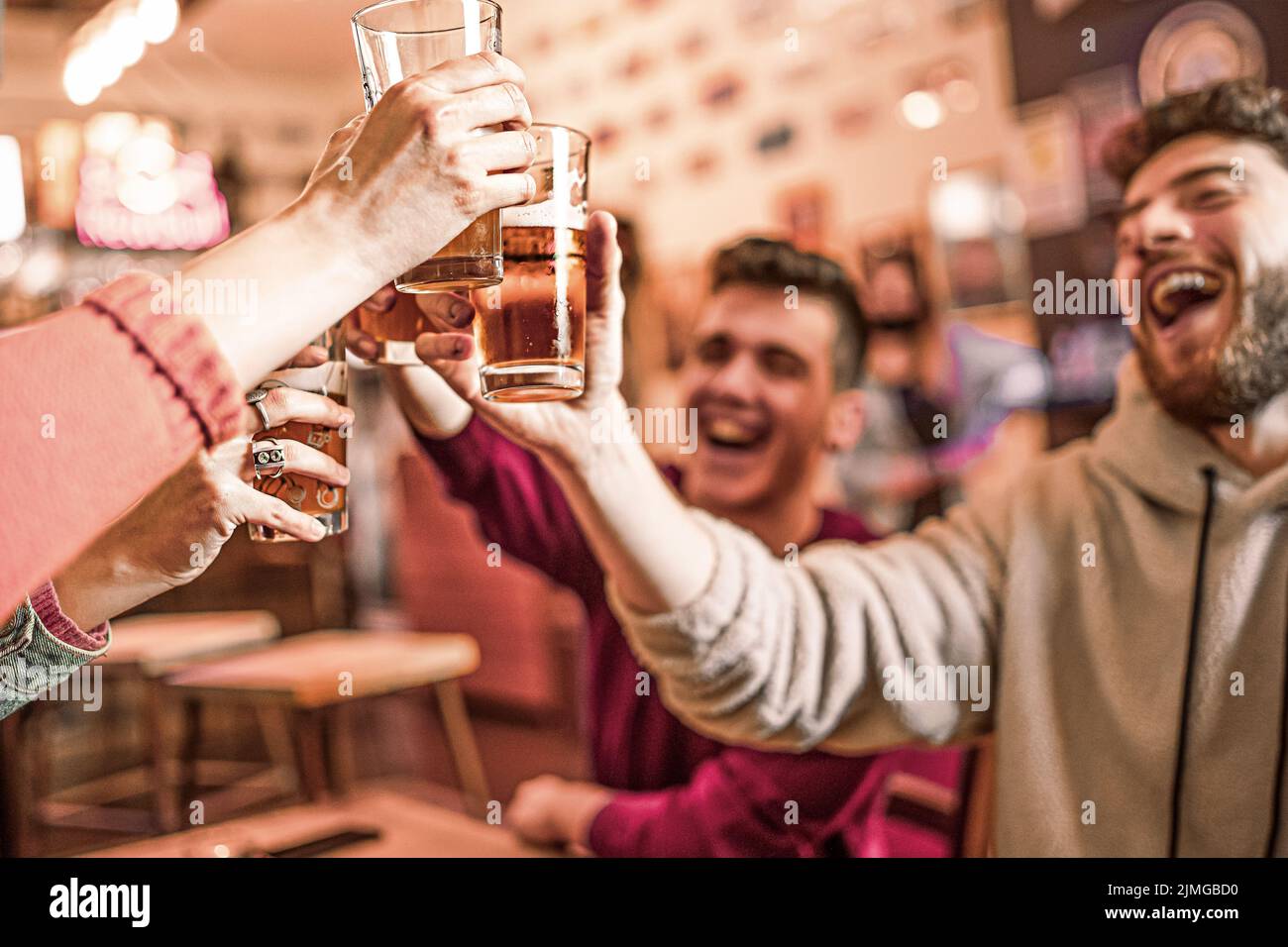 Happy friends at pub cafe raising beer glasses for a celebratory toast ...