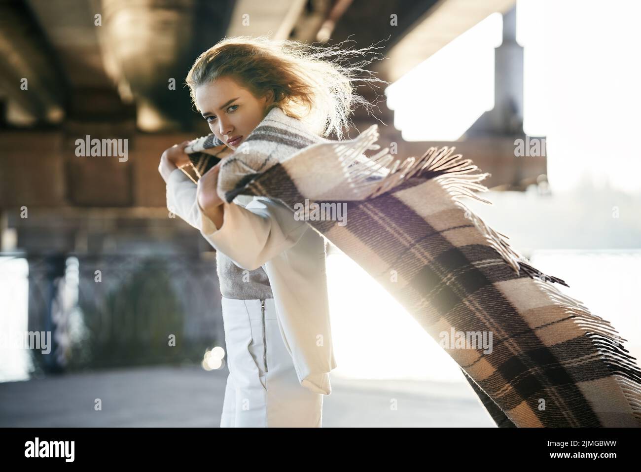 Beautiful young woman with blanket looking to camera on windy sunny day ...
