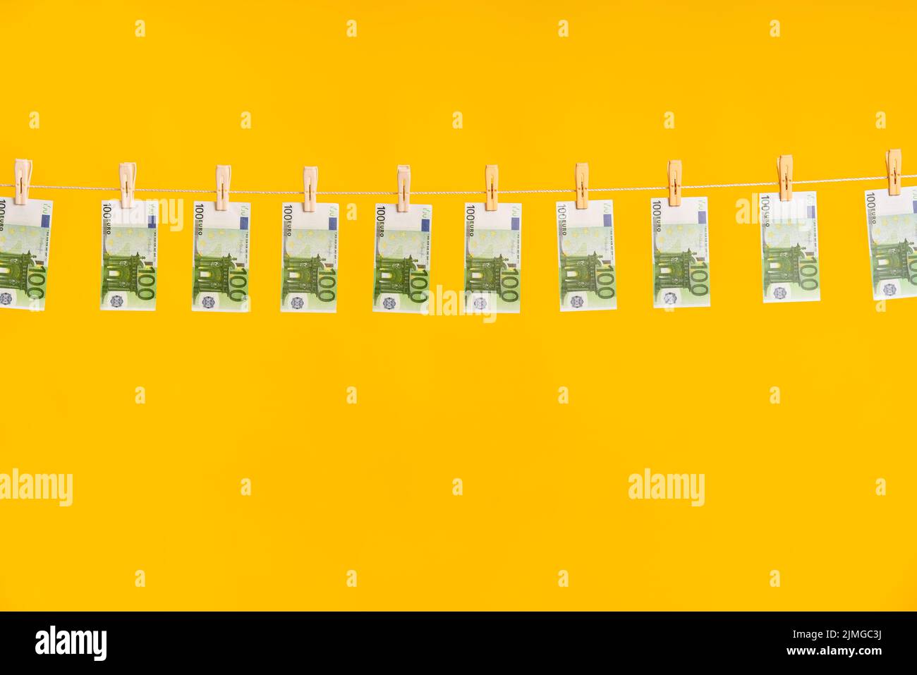 Money laundering, euro banknotes hanging on rope over yellow studio ...