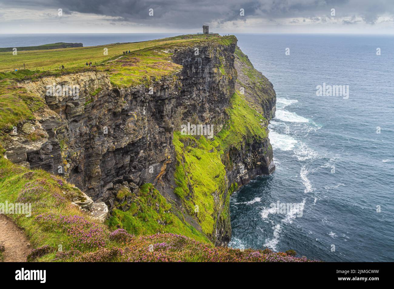 Tourists on a trail to Moher Tower on iconic Cliffs of Moher, Ireland ...