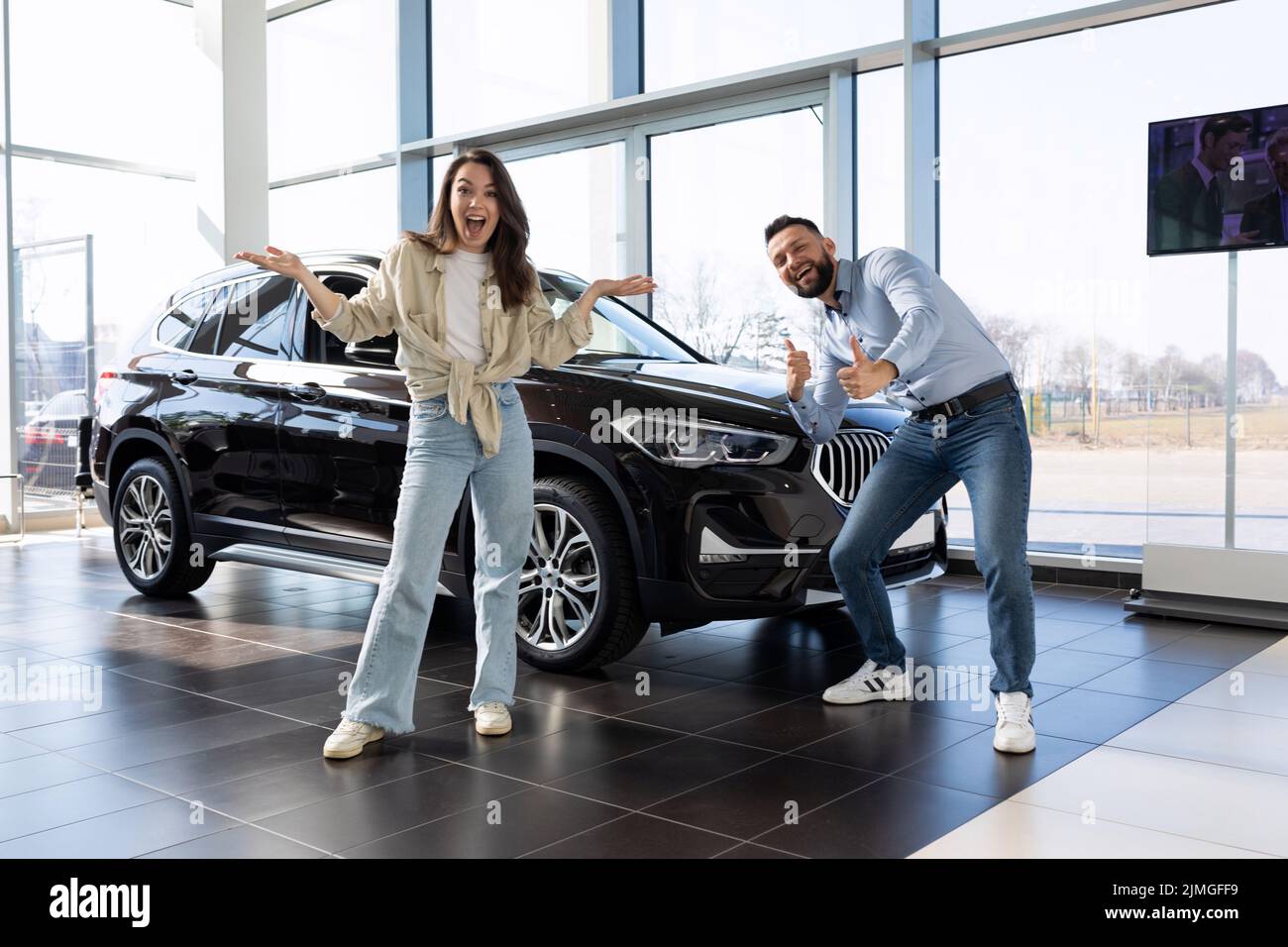 man and woman inspecting a new car before buying in a car dealership ...