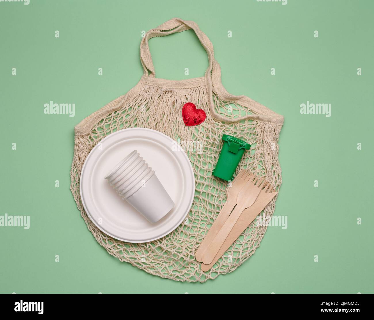 White cotton bag, paper cups and wooden forks and spoons on a green ...