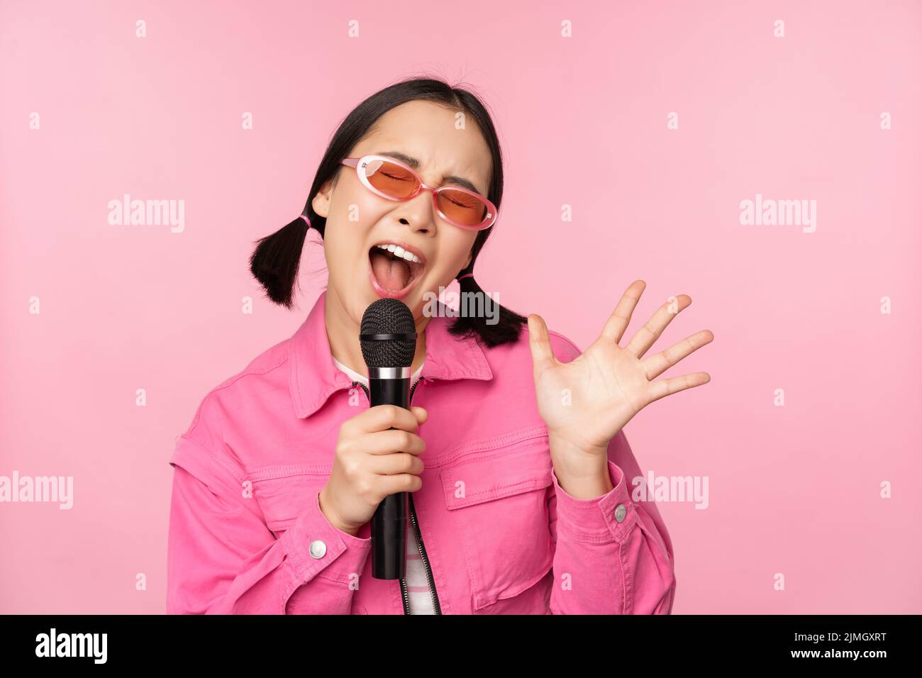 Happy beautiful asian girl singing with mic, using microphone, enjoying ...