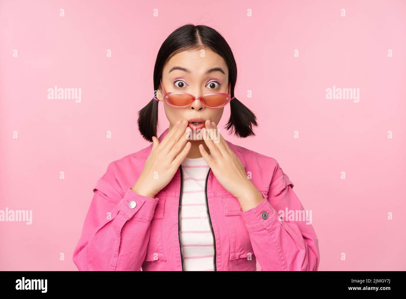 Portrait of young asian woman in stylish sunlgasses, looking surprised ...