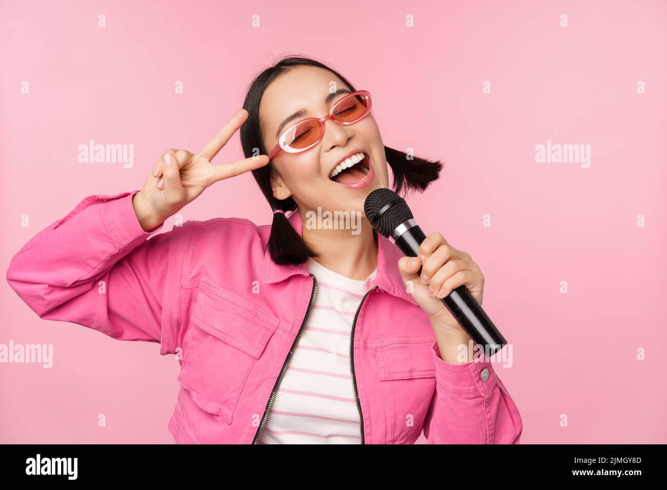 Happy beautiful asian girl singing with mic, using microphone, enjoying ...