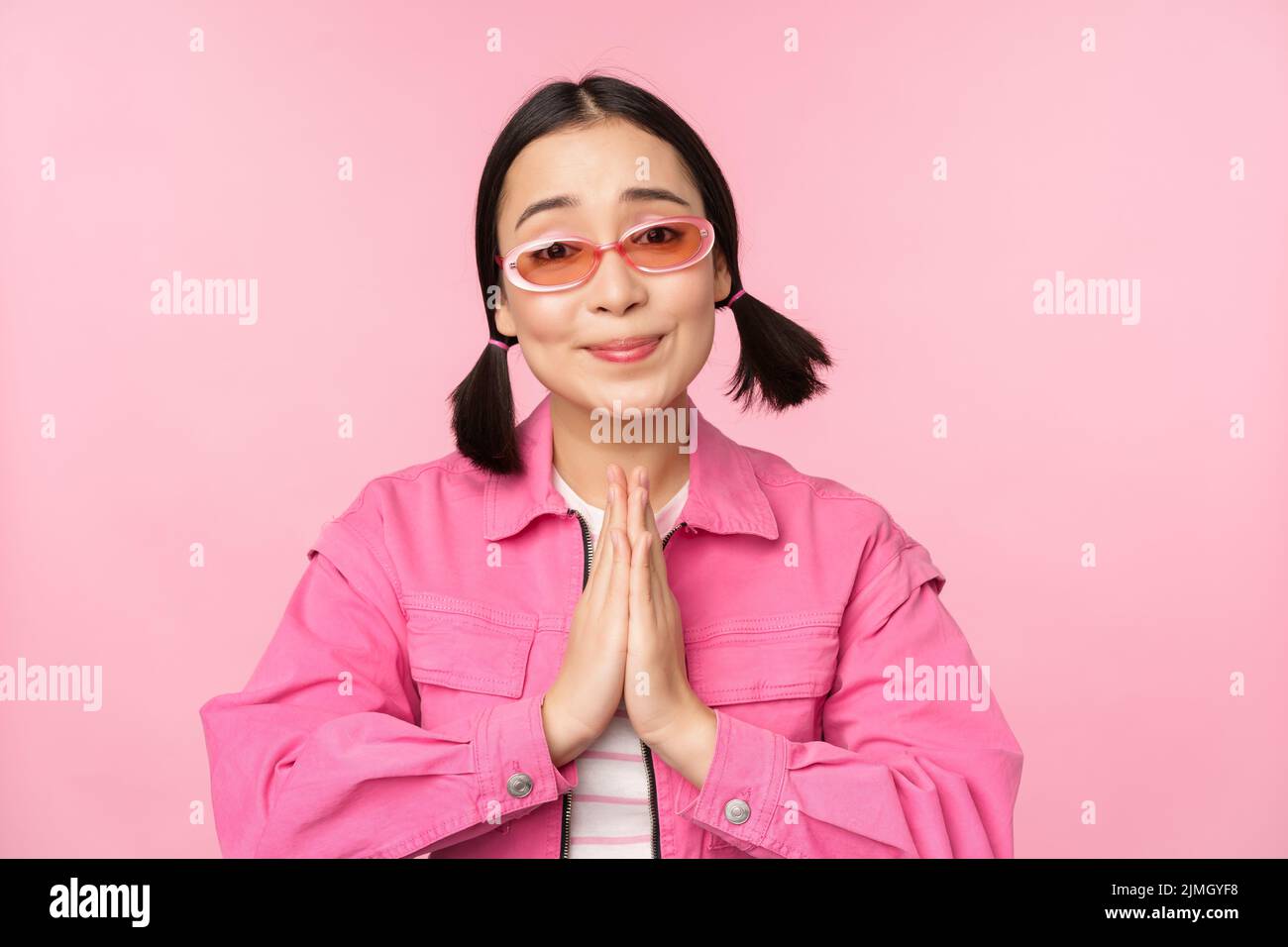 Please. Cute asian girl asking favour, begging, standing against studio ...