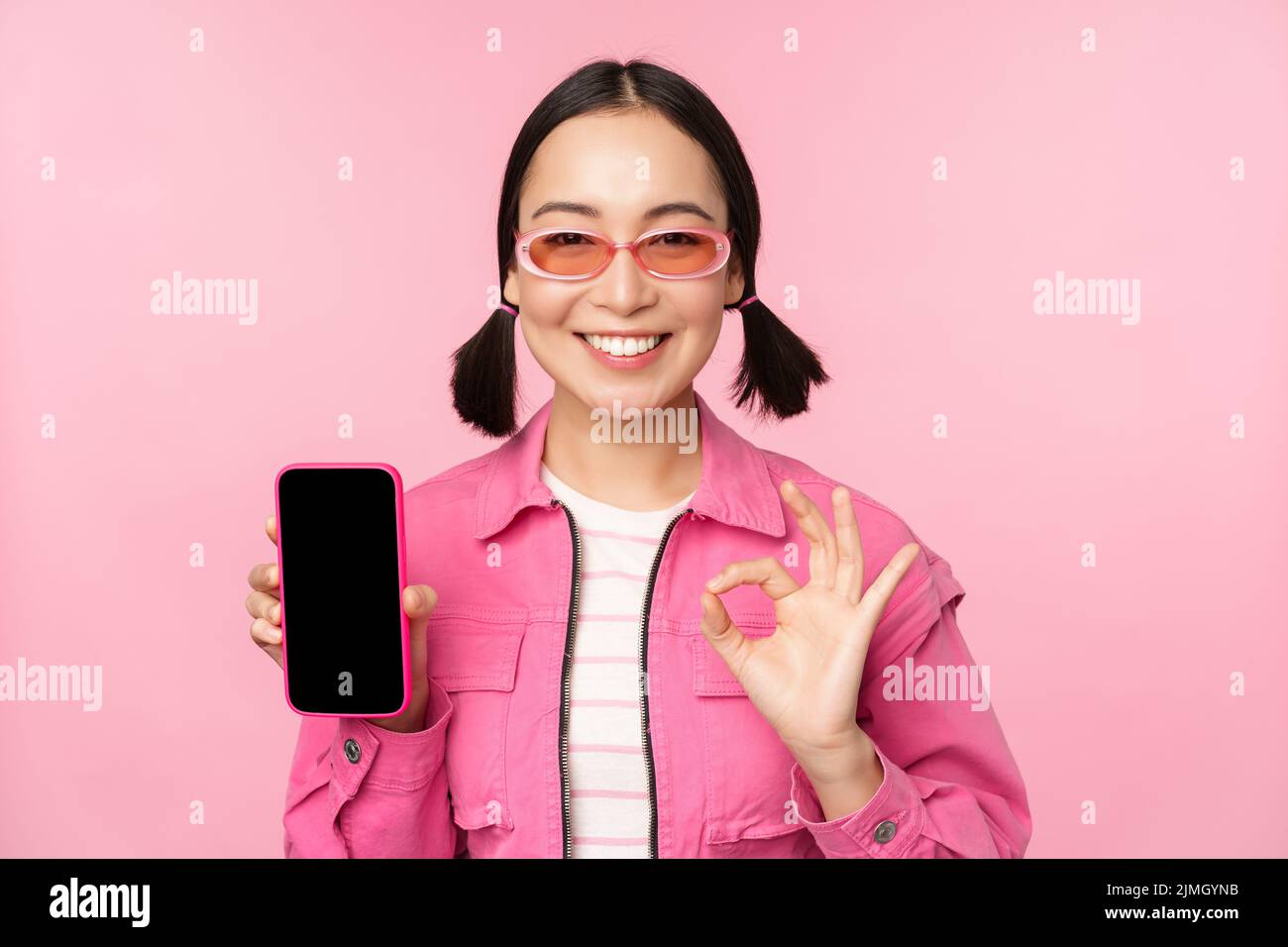 Enthusiastic young asian woman showing okay, ok sign, smiling pleased ...