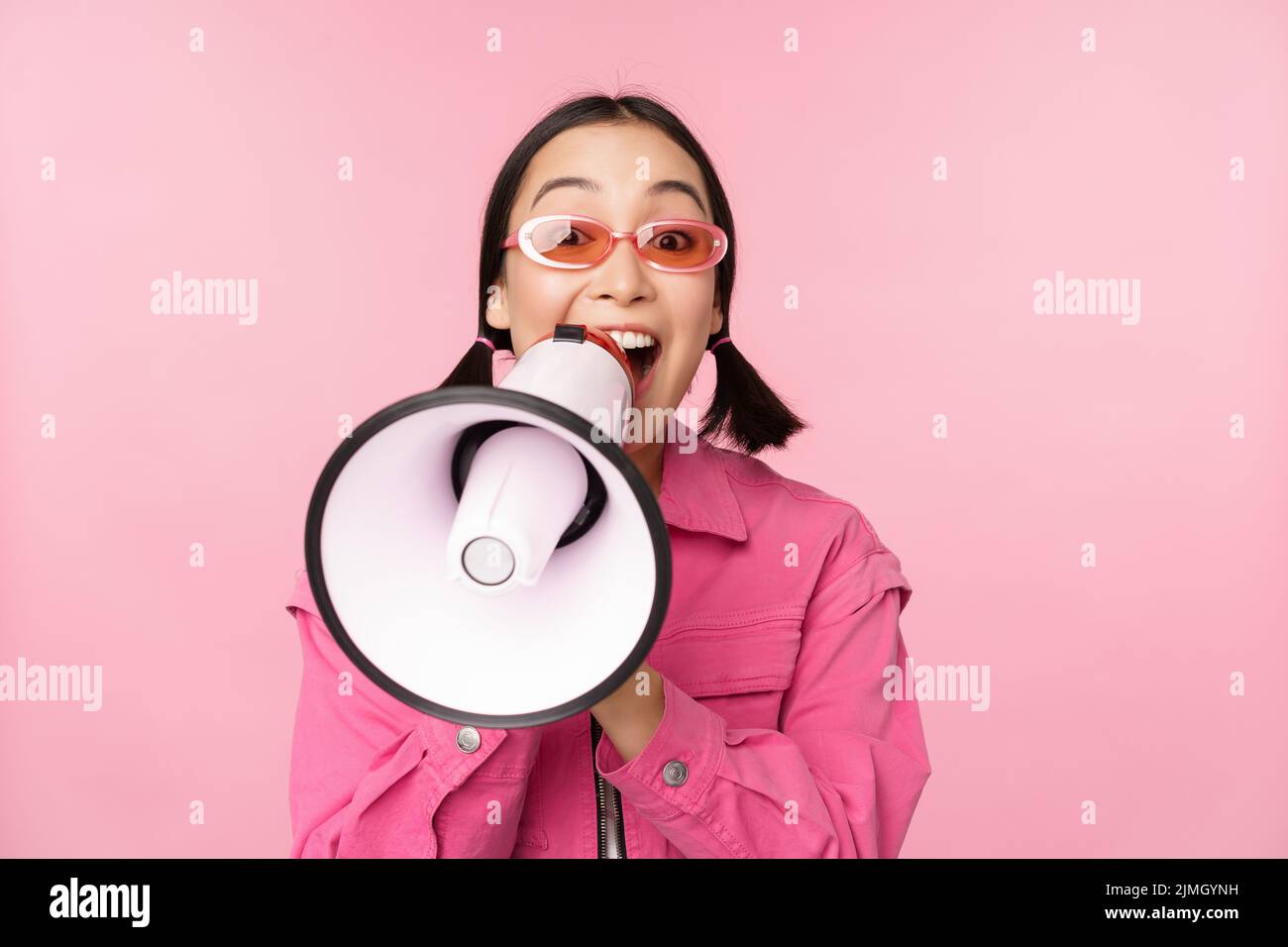 Attention, announcement concept. Enthusiastic asian girl shouting in megaphone, advertising with ...