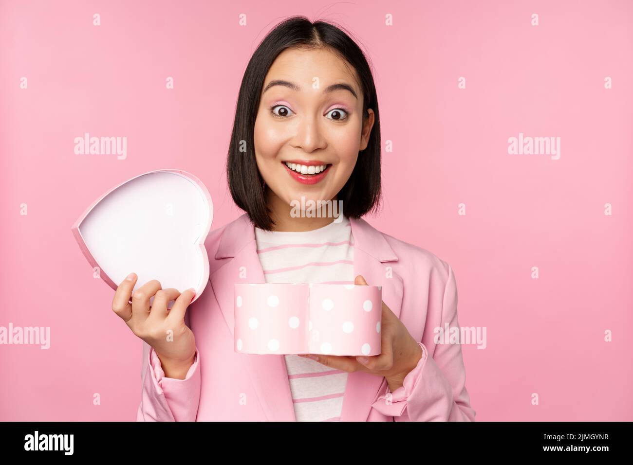Happy cute korean girl in suit, opens up heart shaped box with romantic ...