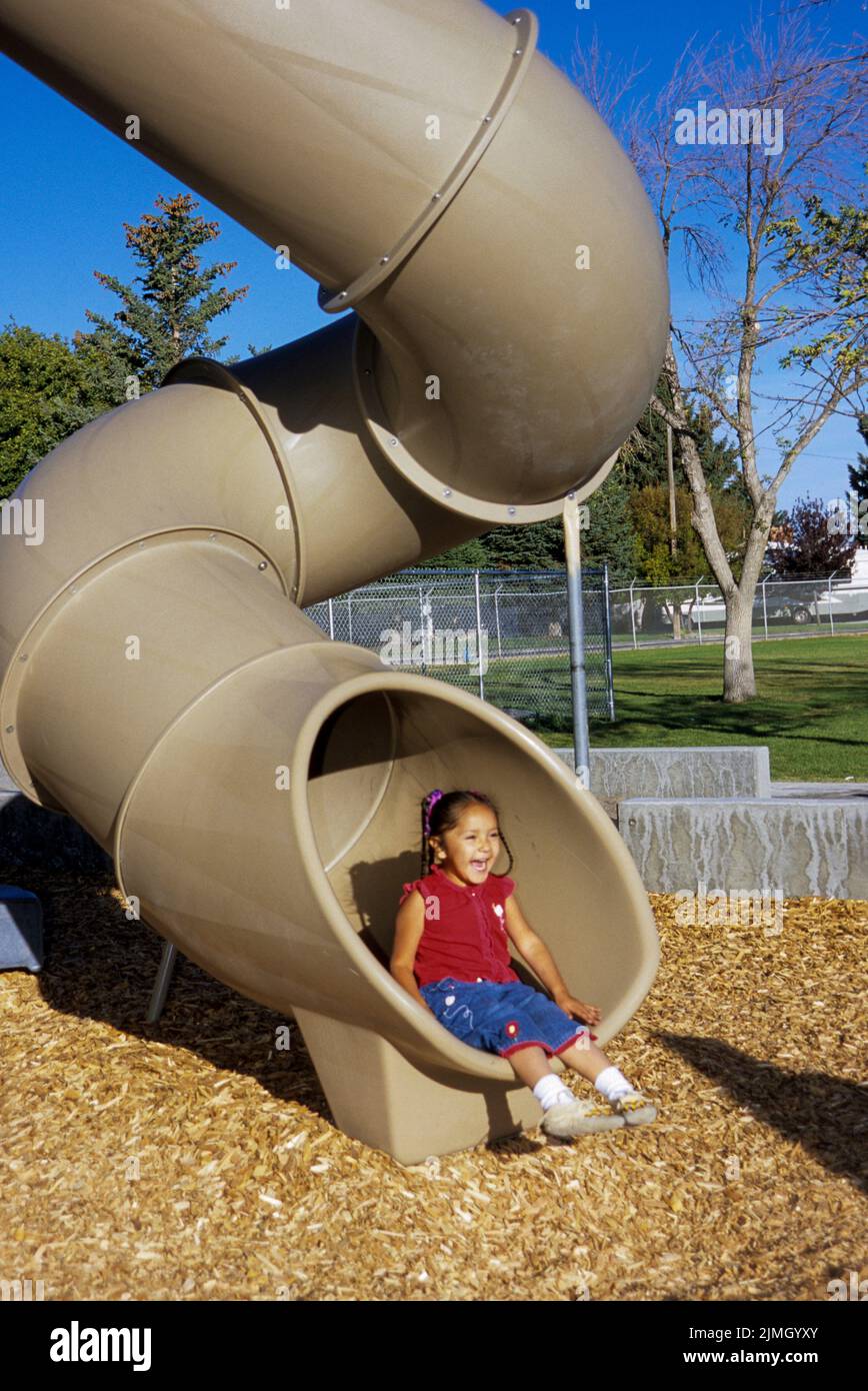Native American girl plays on tube slide at a playground on the Fort ...