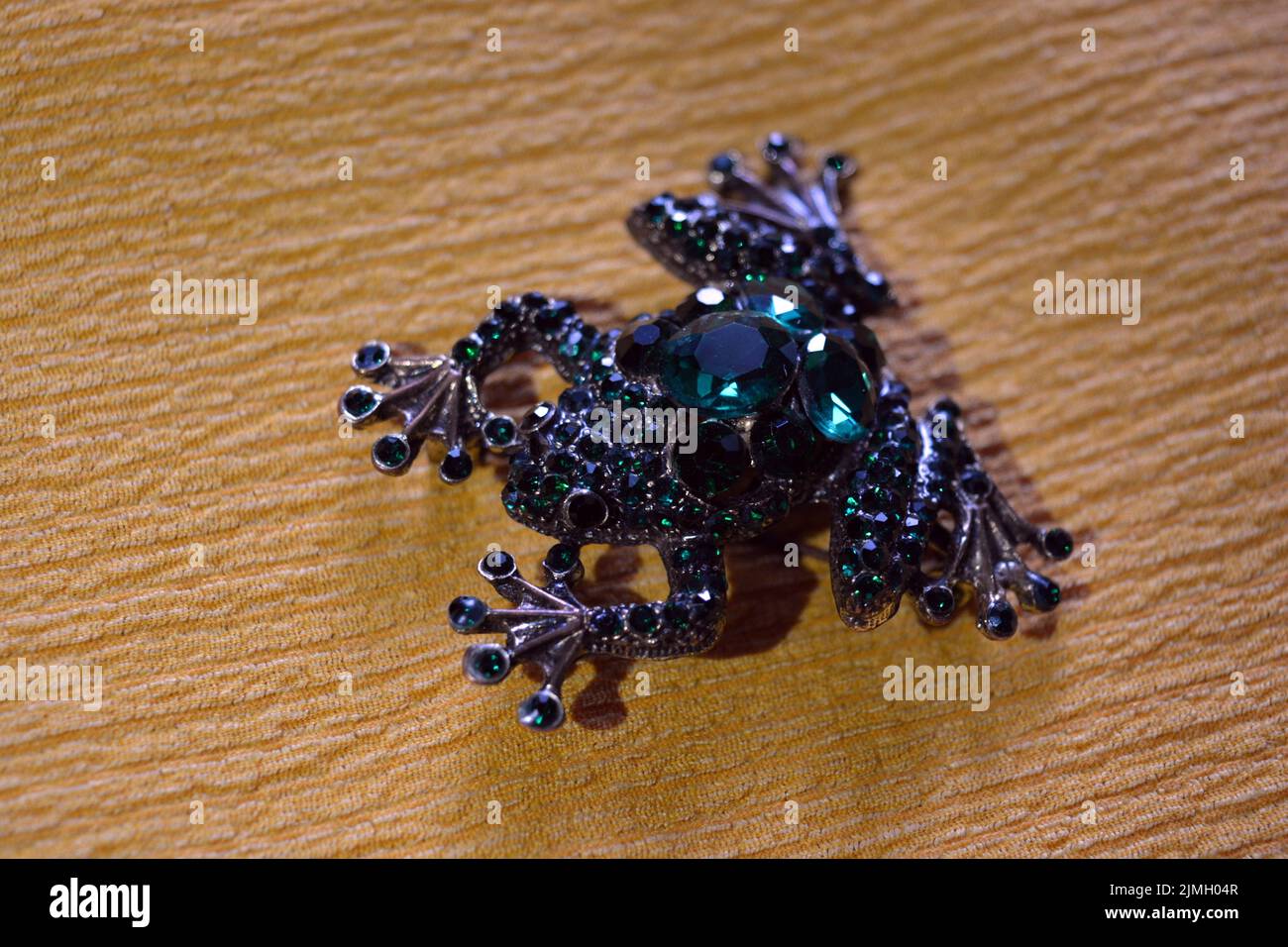 A beautiful female jewelry, a jewel with green stones, a metal frog, a ...